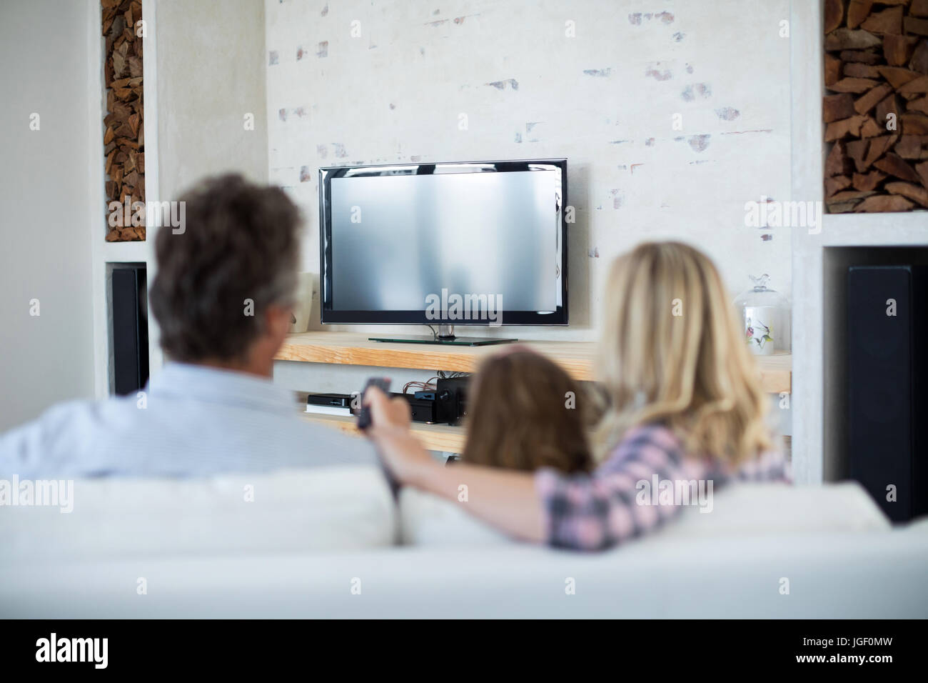 Rear view of family watching television in living room at home Stock ...