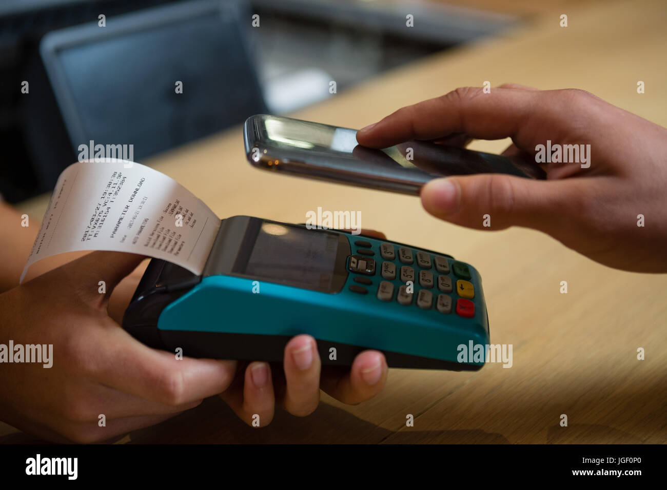 Cropped hand of customer making payment through contactless payment ...