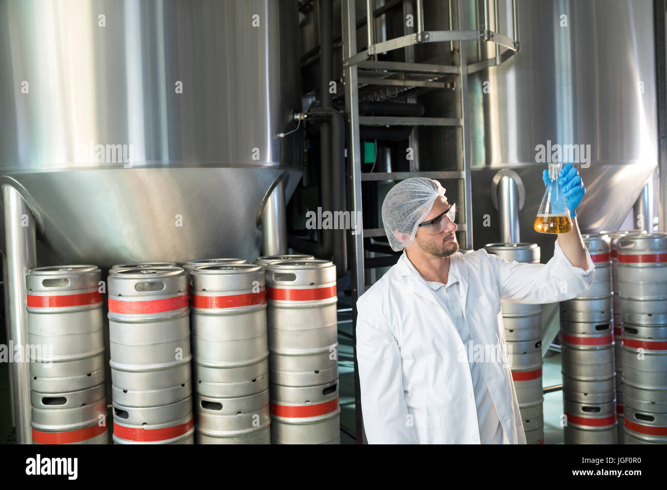Scientist examining beer in beaker at warehouse Stock Photo - Alamy