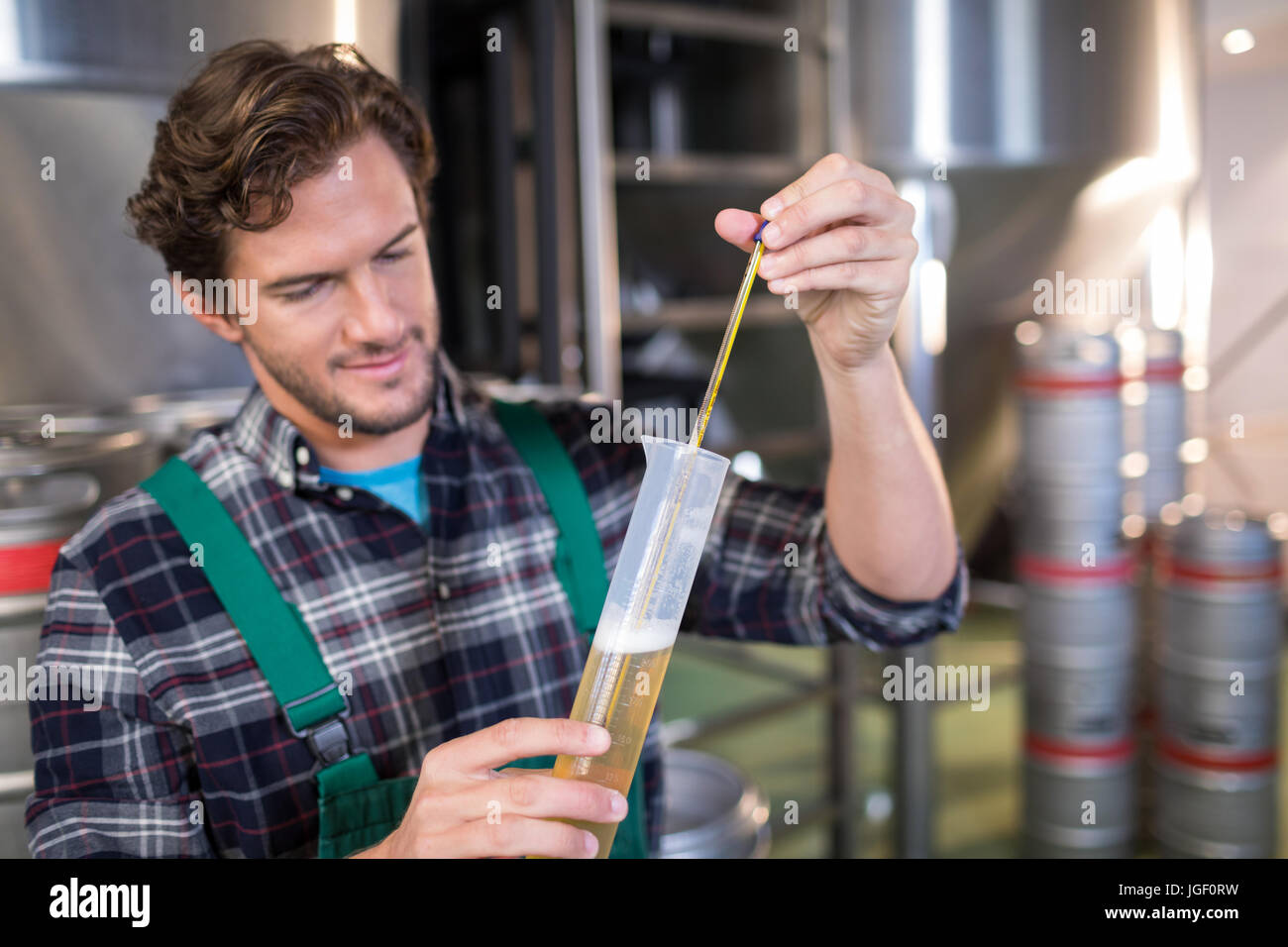 Confident worker examining beer at warehouse Stock Photo - Alamy