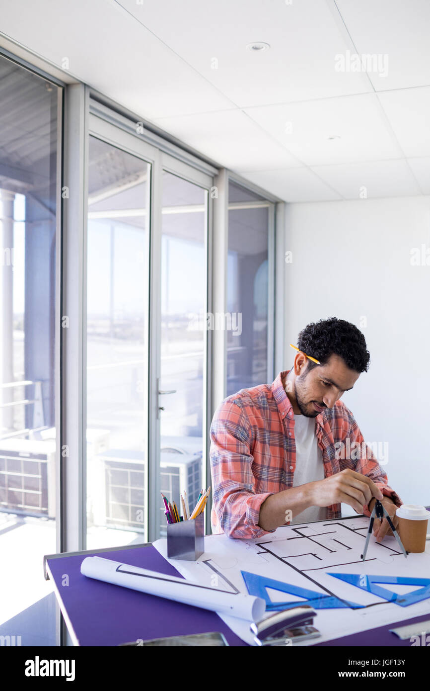 Male architect working on blueprint over drafting table in office Stock ...