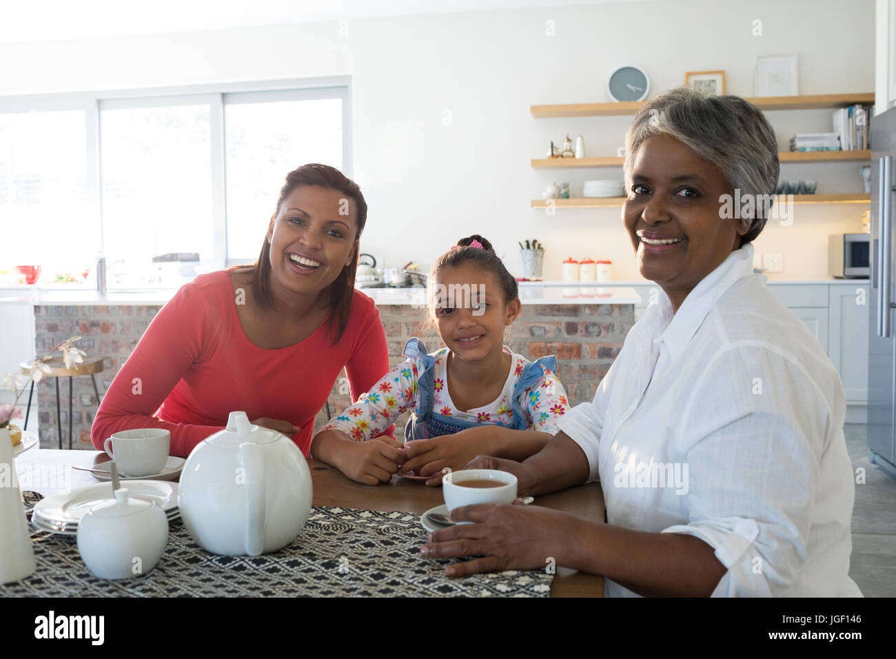 Portrait of happy multi-generation family having tea in dining table at ...