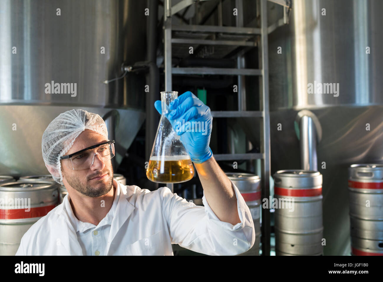 Scientist examining beer in beaker at factory Stock Photo - Alamy