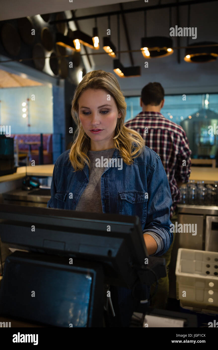Young female owner using cash register at restaurant Stock Photo - Alamy