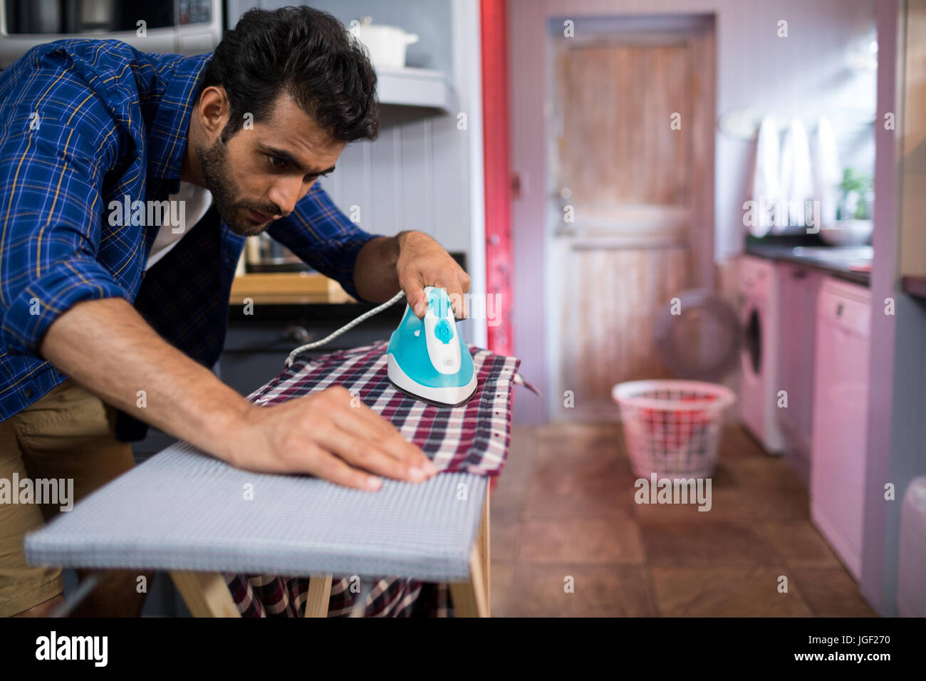 Young man ironing shirt on board at home Stock Photo - Alamy