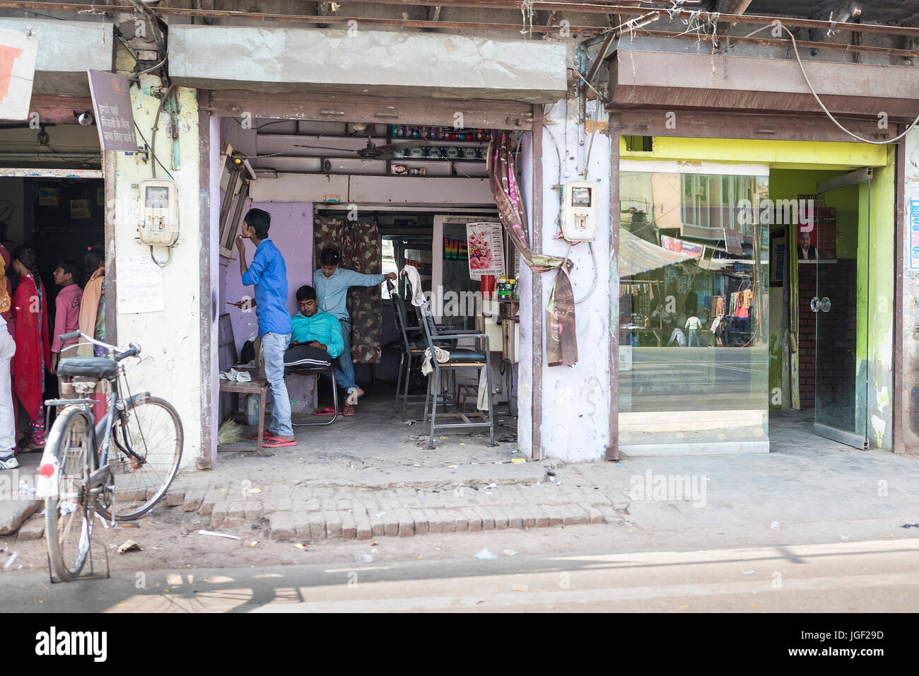 Three men wait for customers in an open fronted barber's shop. One ...