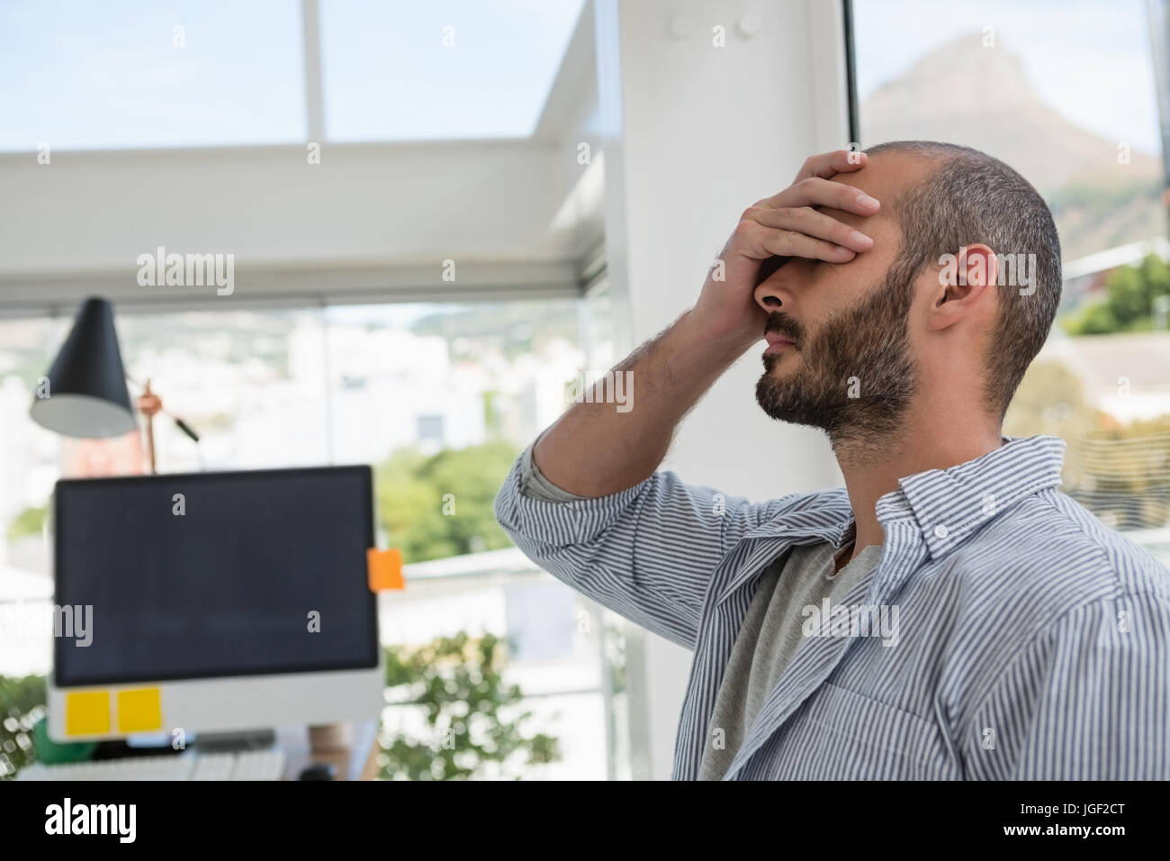 Frustrated designer leaning on glass window at office Stock Photo - Alamy