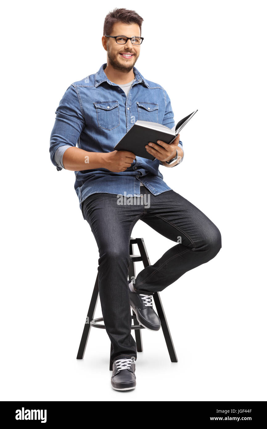 Man with a book sitting on a chair and looking at the camera isolated ...