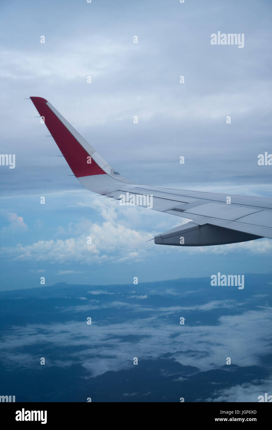 View through the aircraft window of wing over clouds and sky background ...