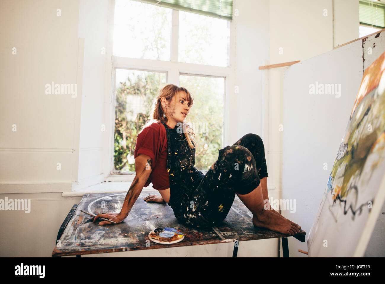 Indoor shot of female painter working in studio. Relaxed young woman ...