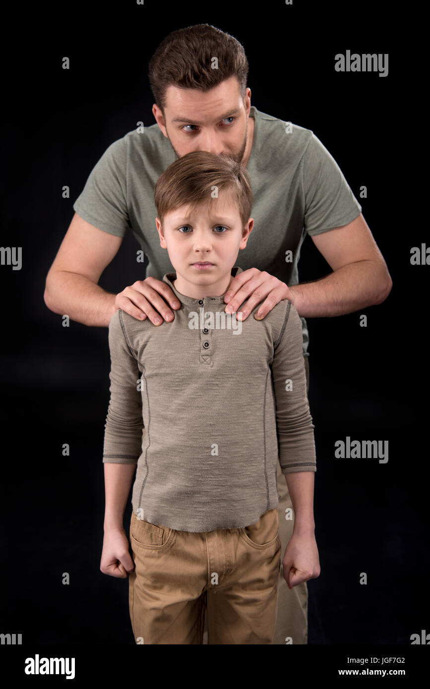 Father putting hands on shoulders of scared little son, family problems ...