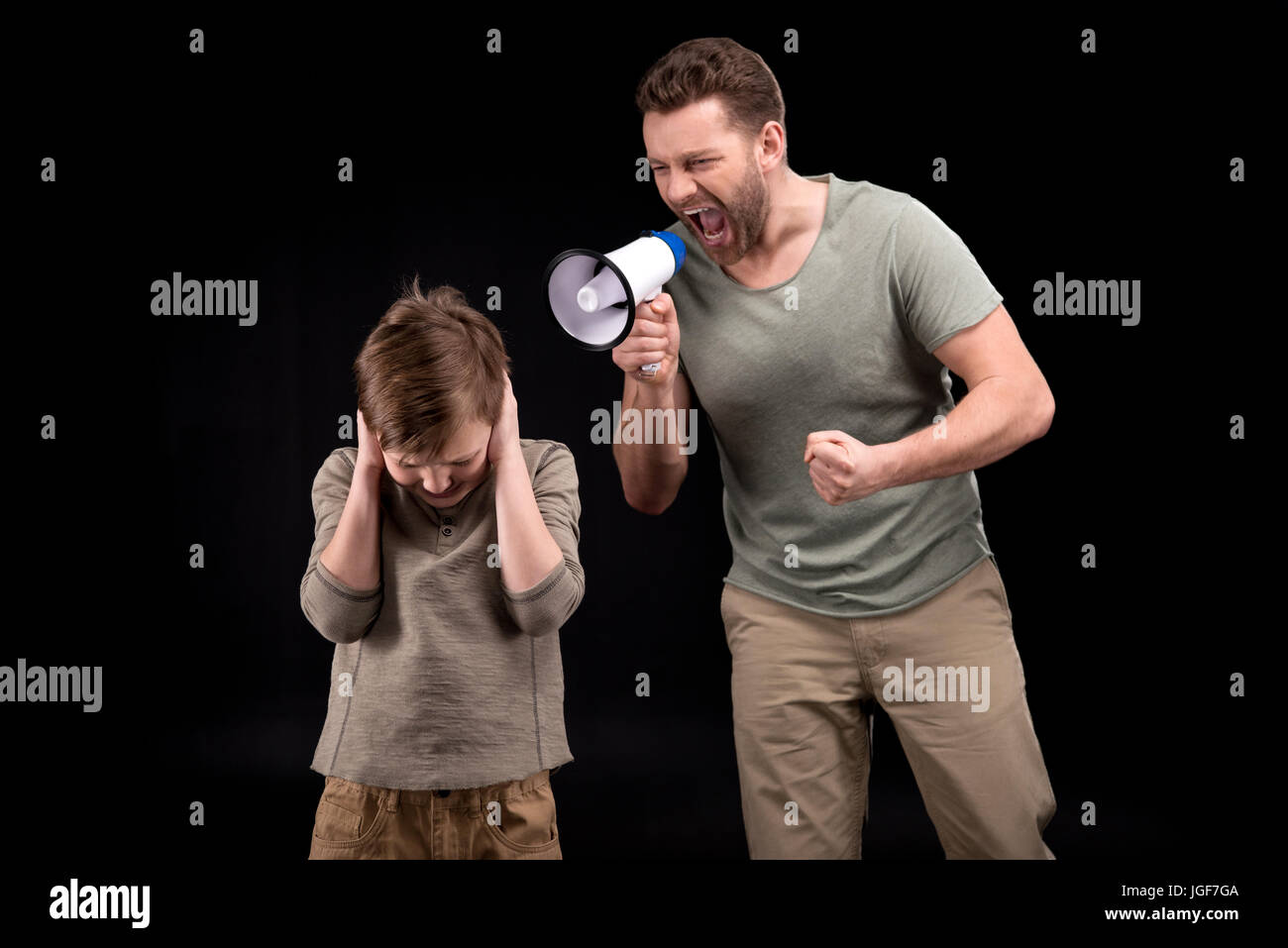 Angry father with megaphone screaming at scared little boy closing ears ...