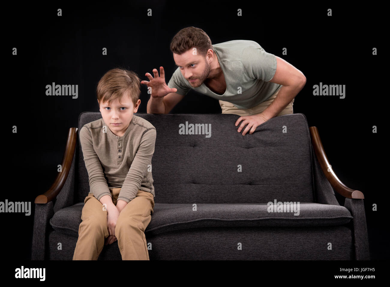 Angry father gesturing to scared little son sitting on sofa, family ...