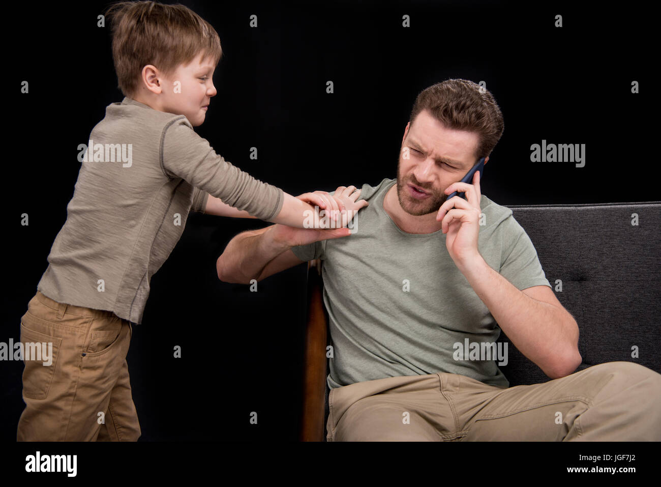 Upset little boy trying to talk with father talking on smartphone ...