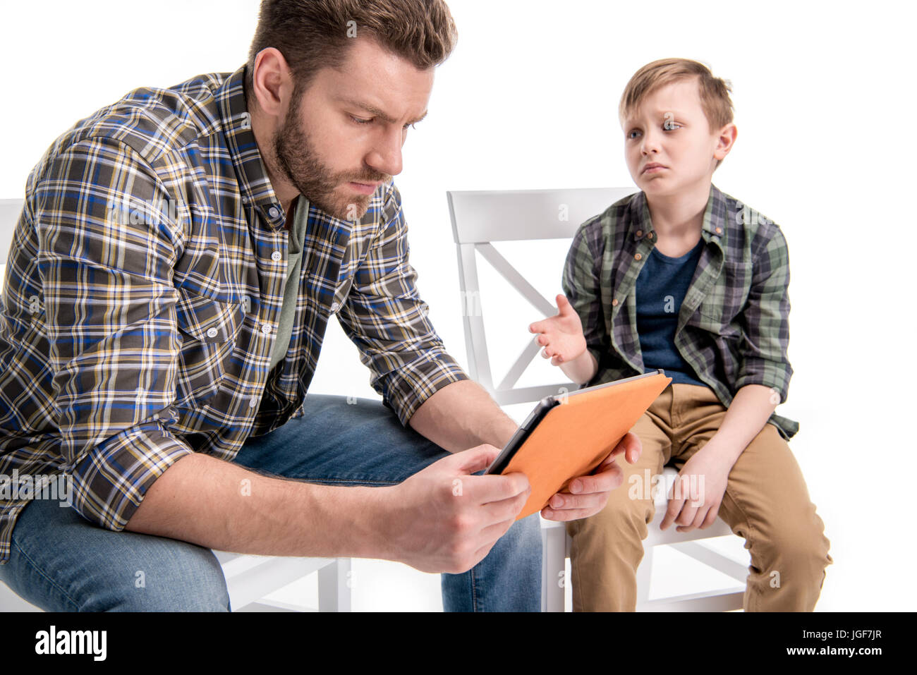 Upset little boy trying to talk with father using digital tablet ...