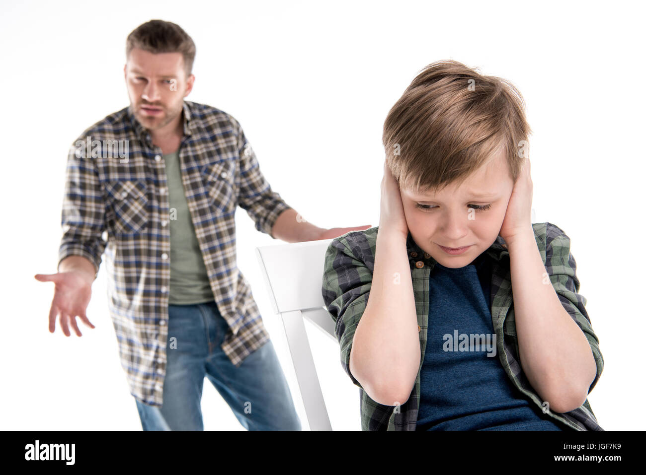 Father gesturing and quarreling with scared little boy closing ears ...