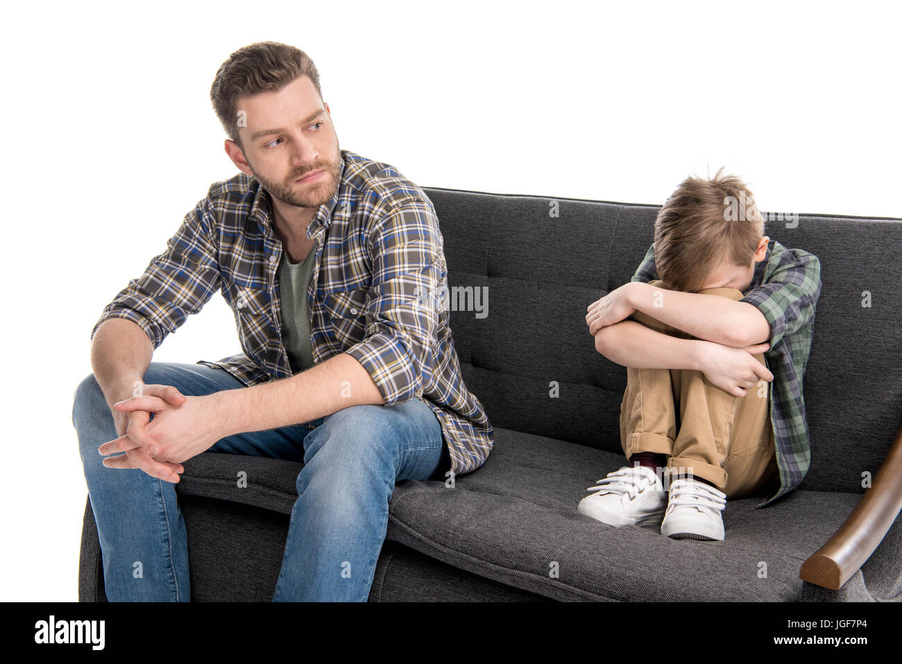 Father sitting on sofa near scared little son, family problems concept ...