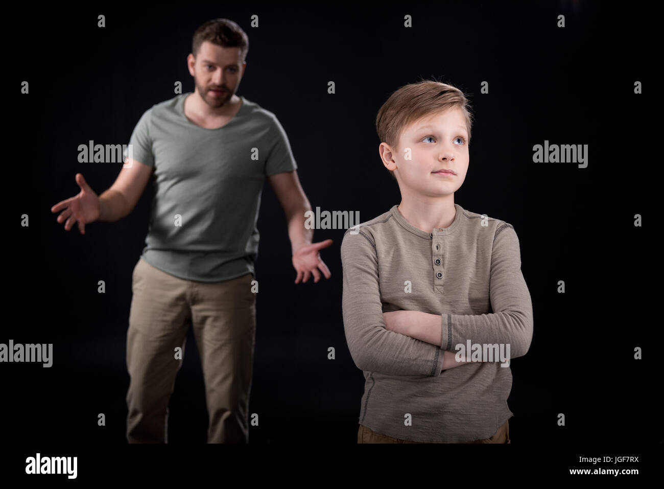 Father quarreling at indifferent son standing with crossed arms, family ...
