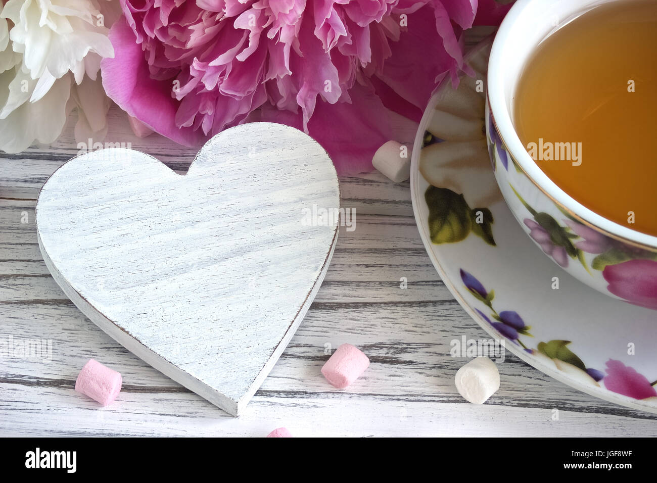 Peonies flowers pink cup of tea rattan hearts marshmallow on a white wooden background - stock ...