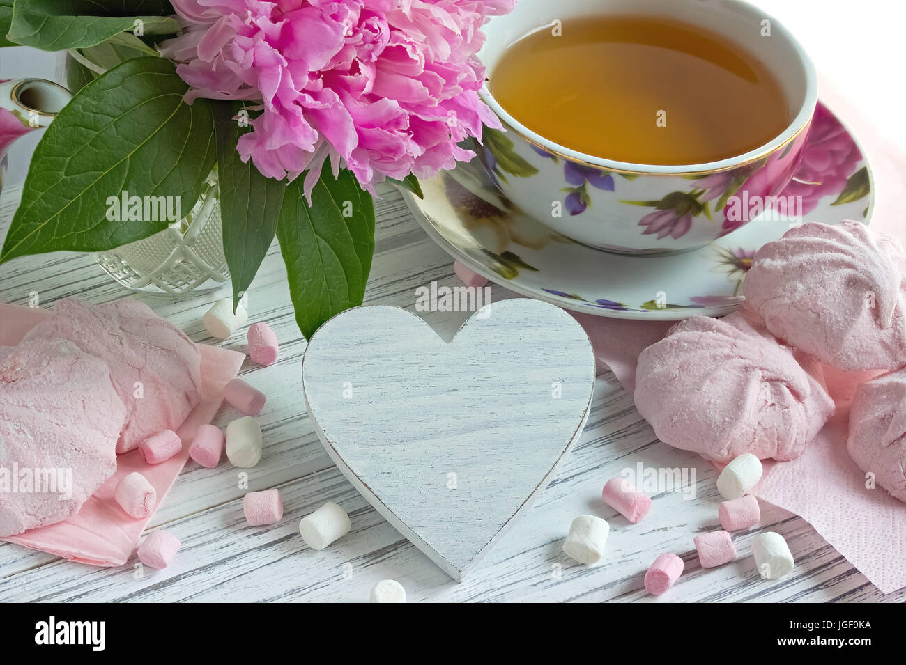 Peonies flowers pink cup of tea rattan hearts marshmallow on a white wooden background - stock ...