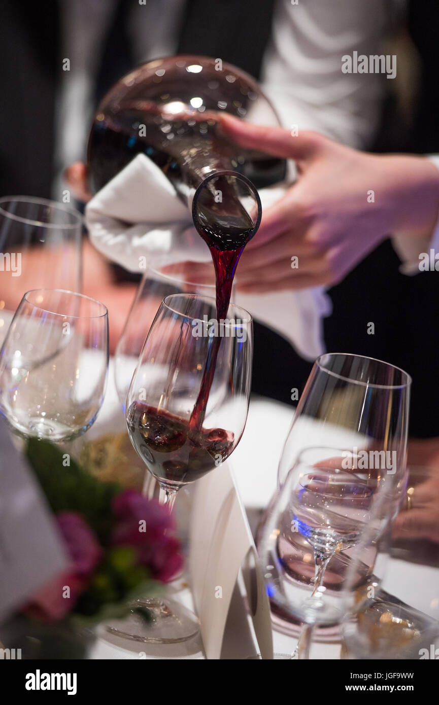 Sommelier pouring wine into glass from mixing bowl at luxury diner ...