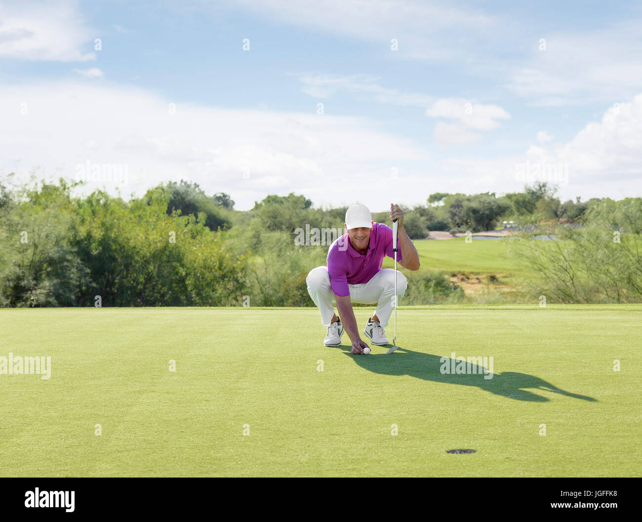 Hispanic golfer crouching on golf course Stock Photo - Alamy
