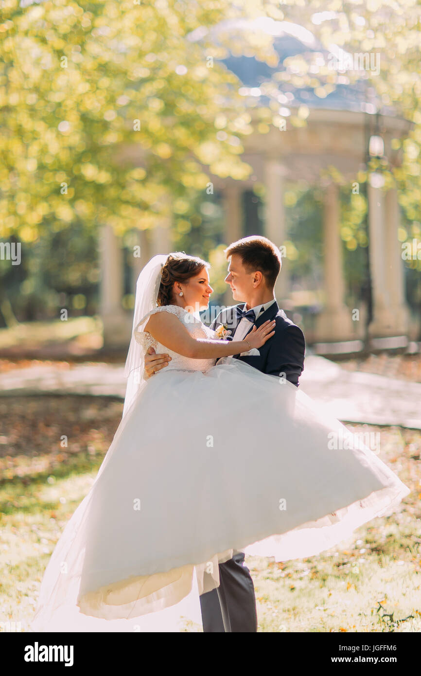 The close-up view of the groom carrying the bride at the background of ...