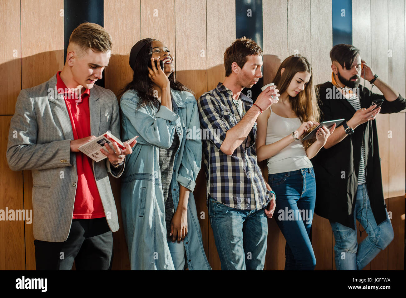 Group of friends standing near the wall in the room. Talking on the ...