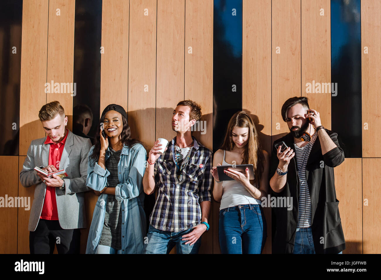 Group of young people relaxing in the big room. People standing near ...