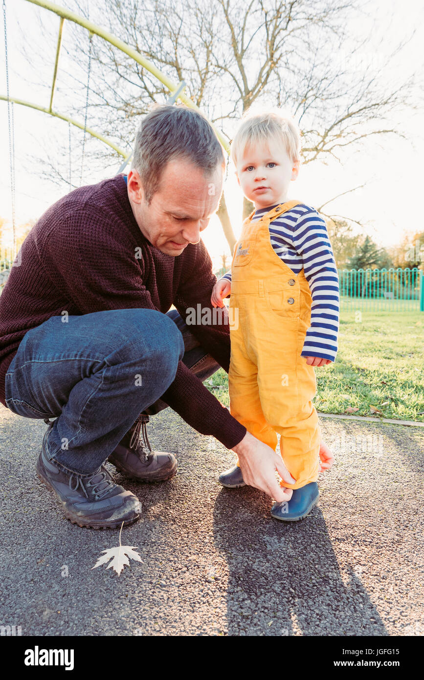 Caucasian father adjusting pants for son Stock Photo - Alamy