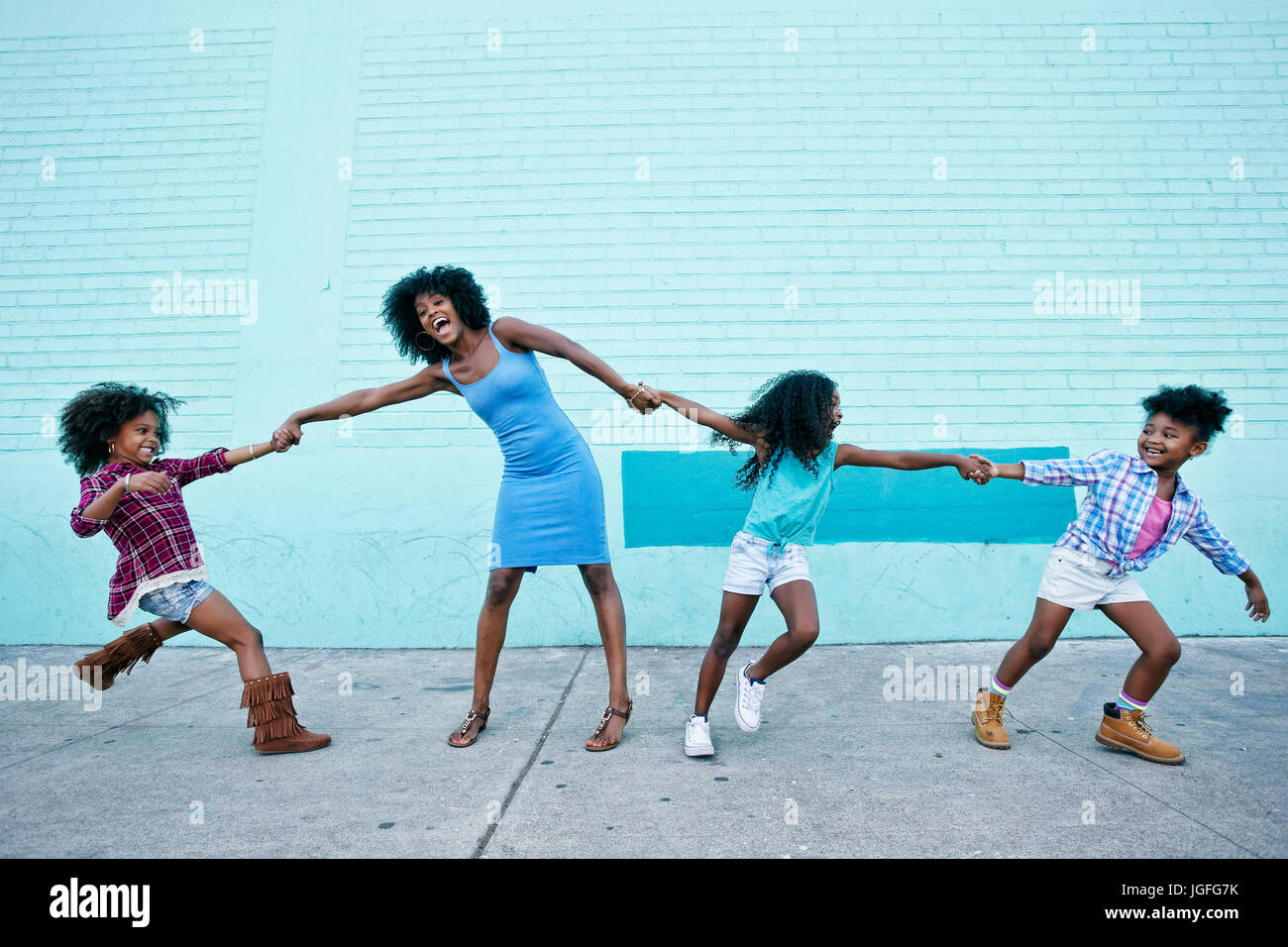 Girls pulling arms of woman in opposite directions Stock Photo - Alamy