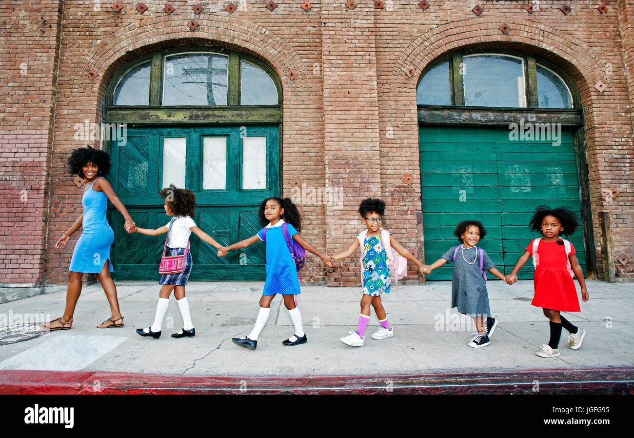 Woman leading girls holding hands on city sidewalk Stock Photo - Alamy