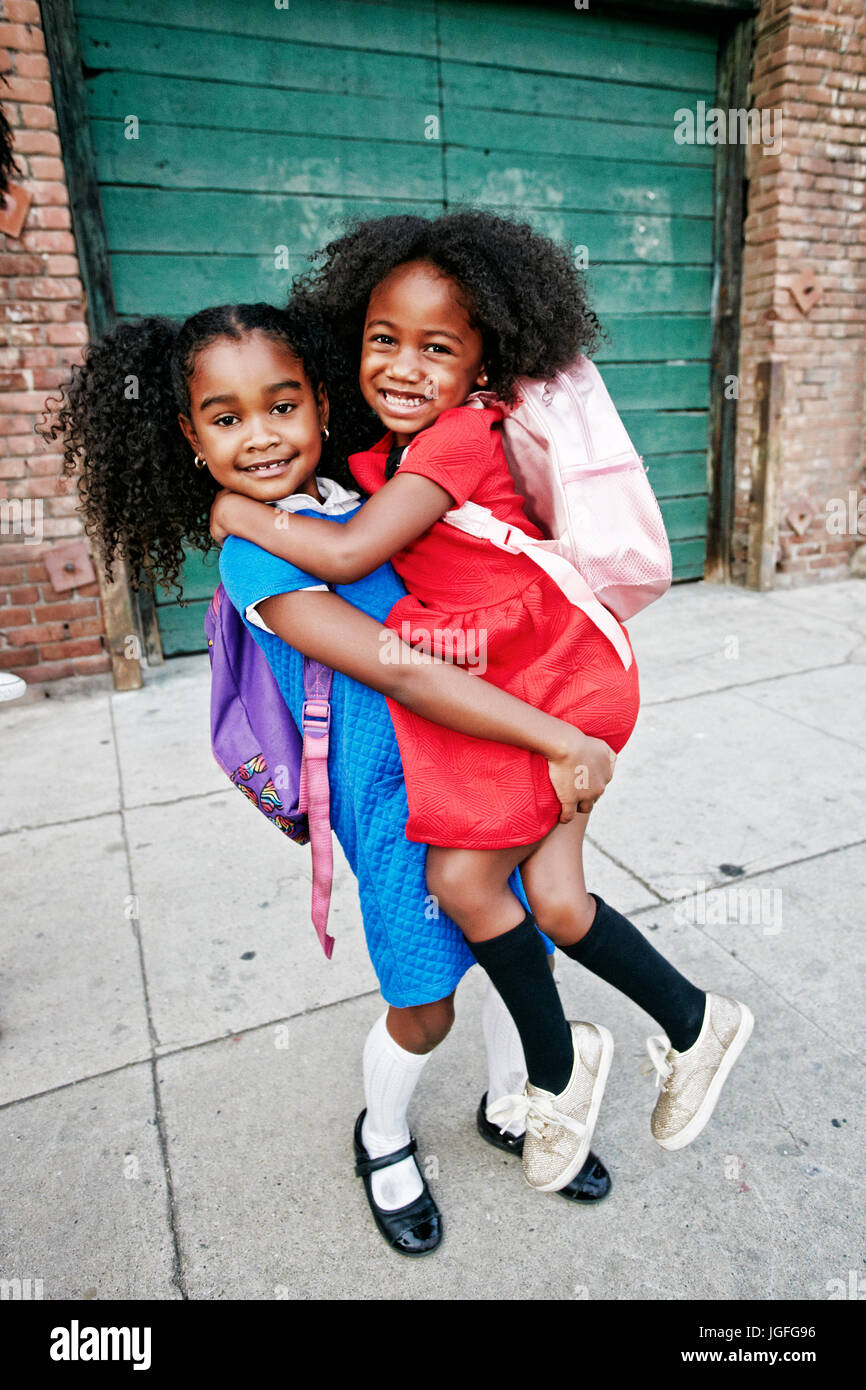 Portrait of smiling girl lifting friend on sidewalk Stock Photo - Alamy