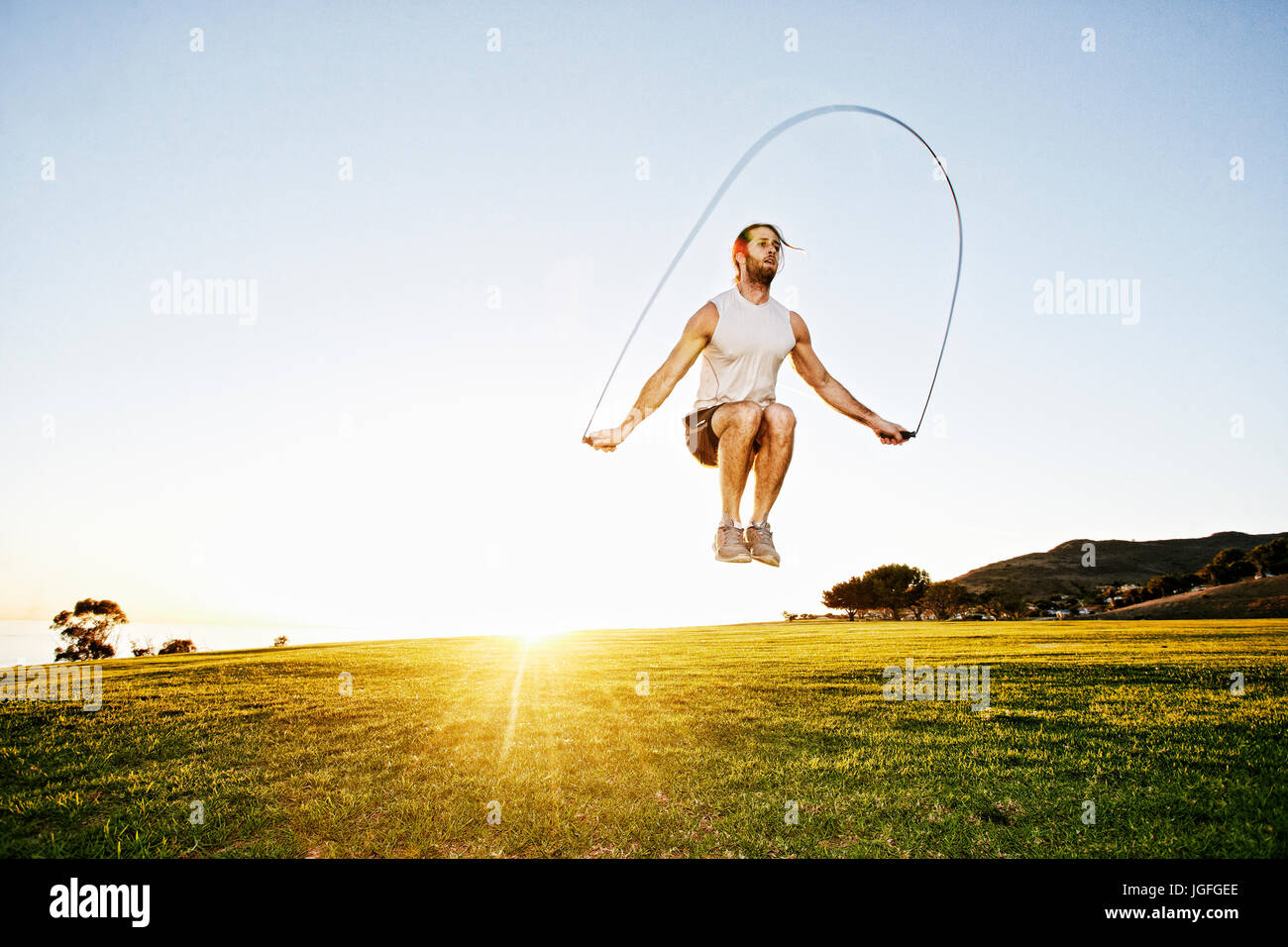 Caucasian man jumping rope in sunny field Stock Photo - Alamy