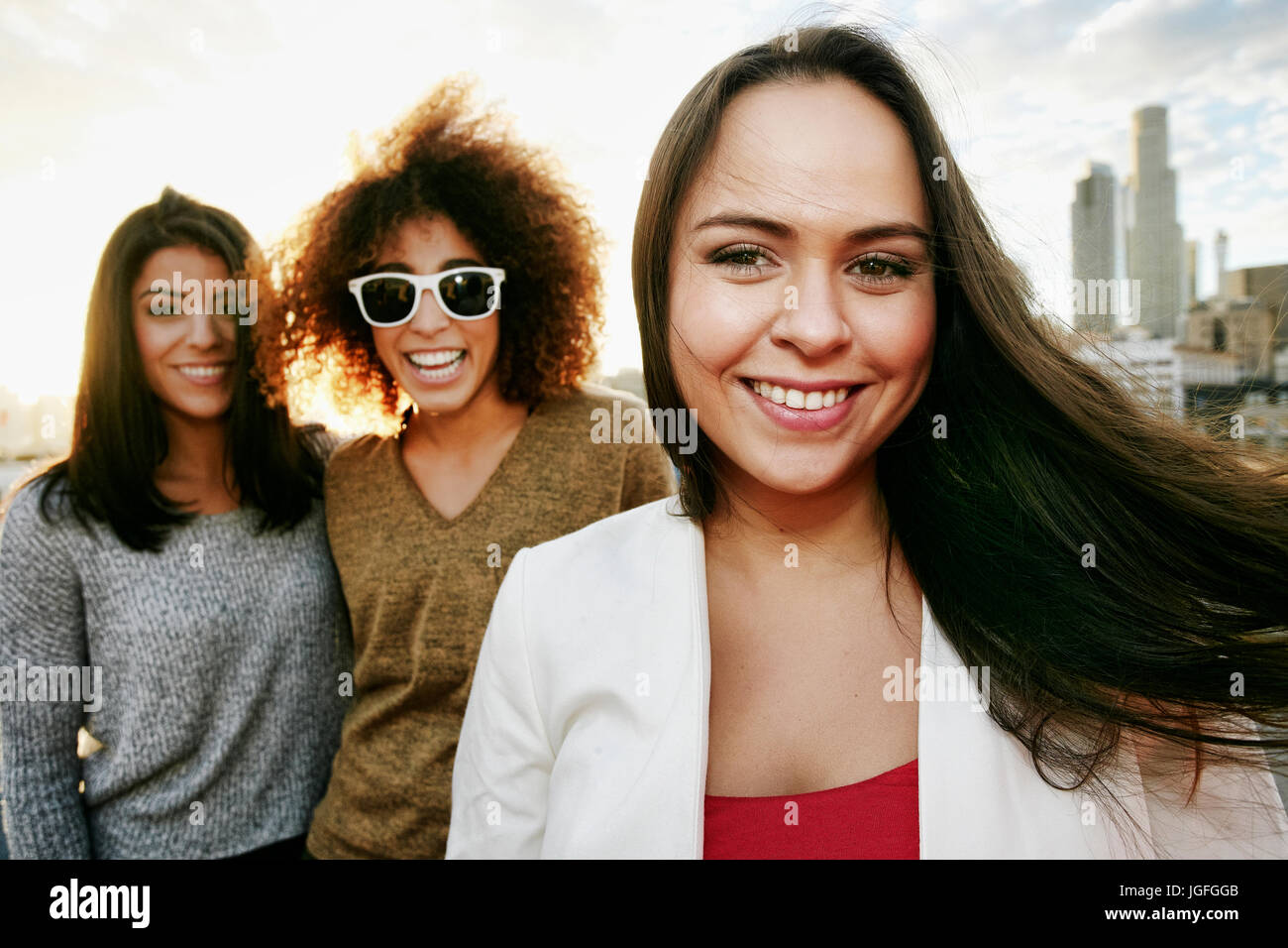 Portrait of smiling women on urban rooftop at sunset Stock Photo - Alamy