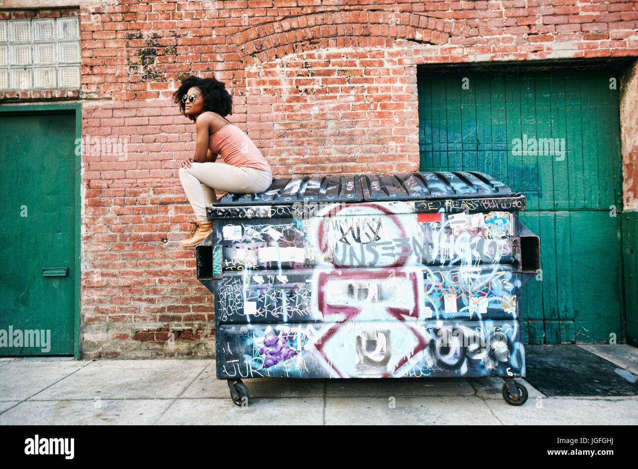 Black woman sitting on dumpster covered with graffiti Stock Photo - Alamy
