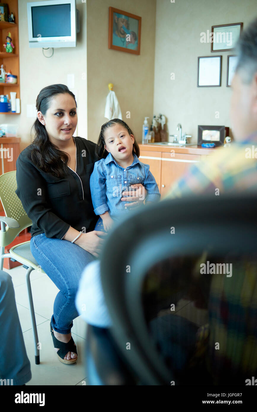 Hispanic mother and daughter with Down Syndrome talking to doctor Stock ...
