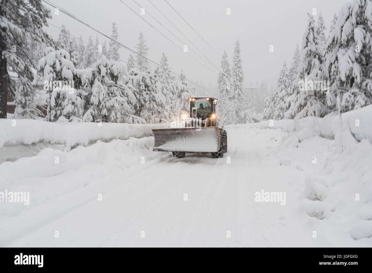 Tractor with snow plow driving on remote road Stock Photo - Alamy