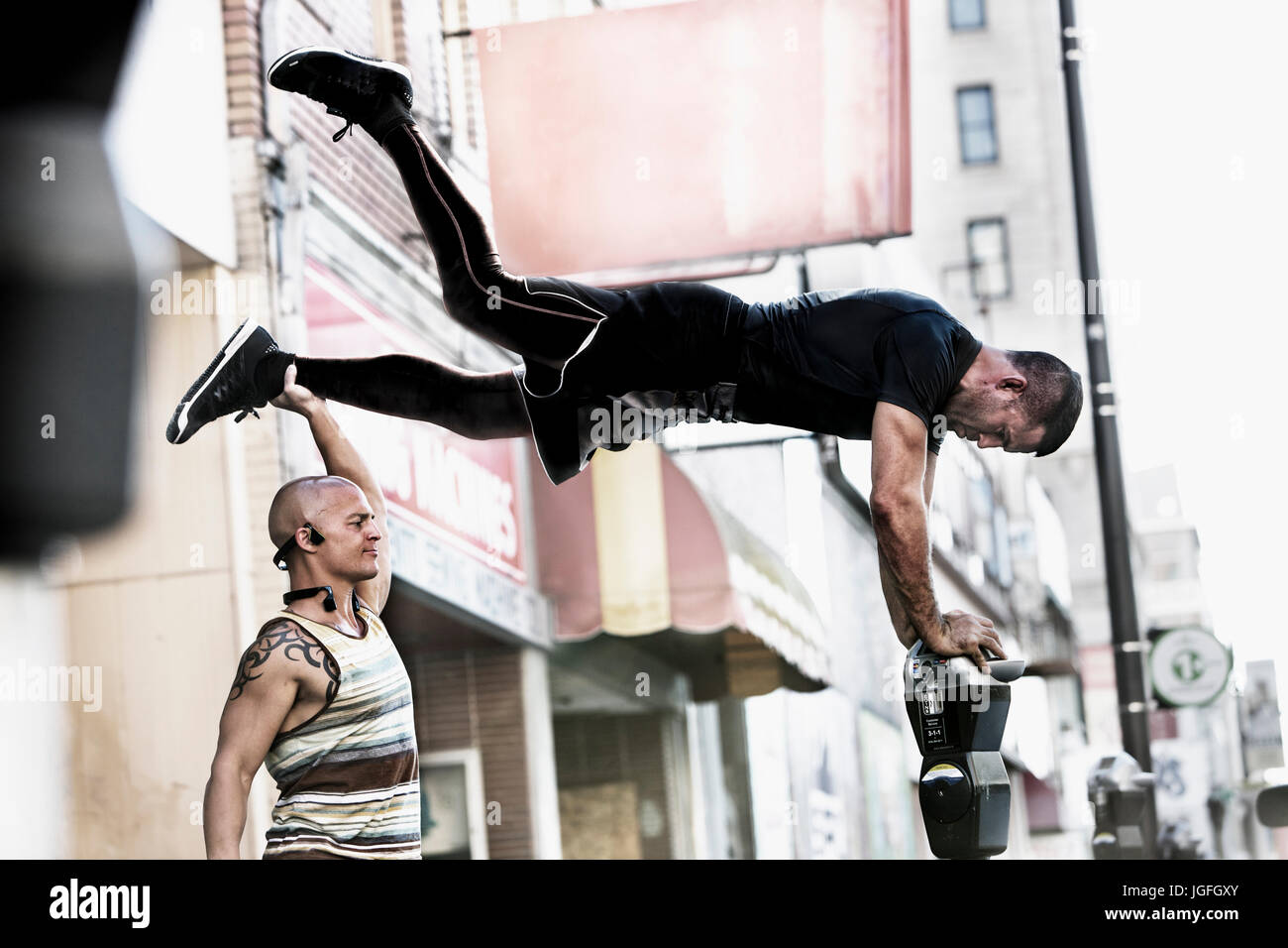 Caucasian man holding leg of friend balancing on parking meter Stock ...
