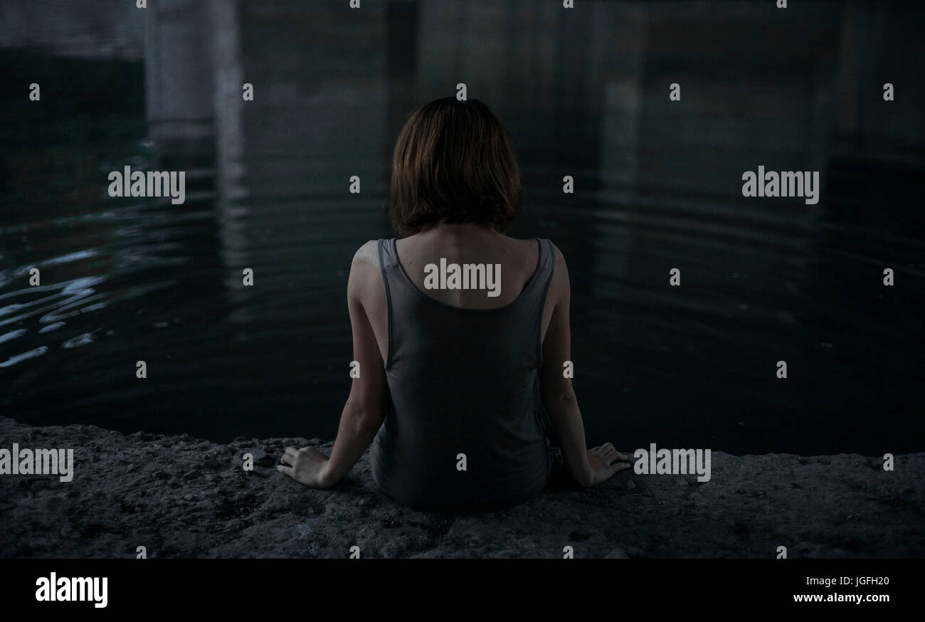 Caucasian woman sitting at edge of water Stock Photo - Alamy