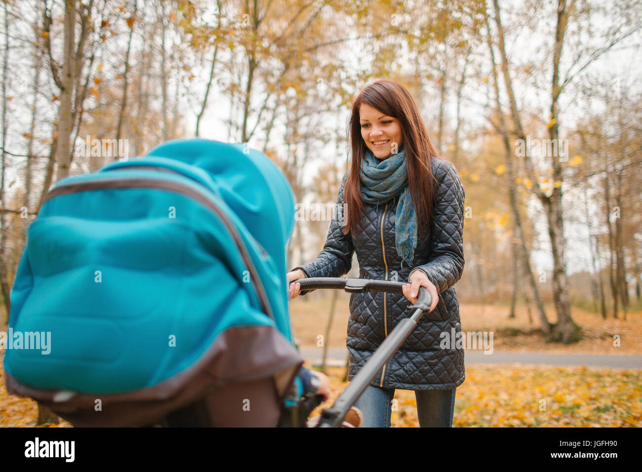 Smiling Middle Eastern woman pushing stroller in park Stock Photo - Alamy