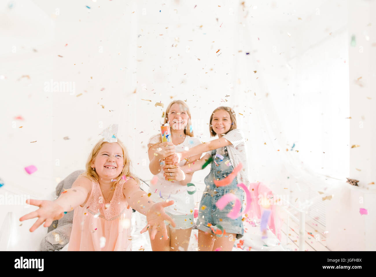 Smiling Middle Eastern girls throwing confetti in bedroom Stock Photo ...