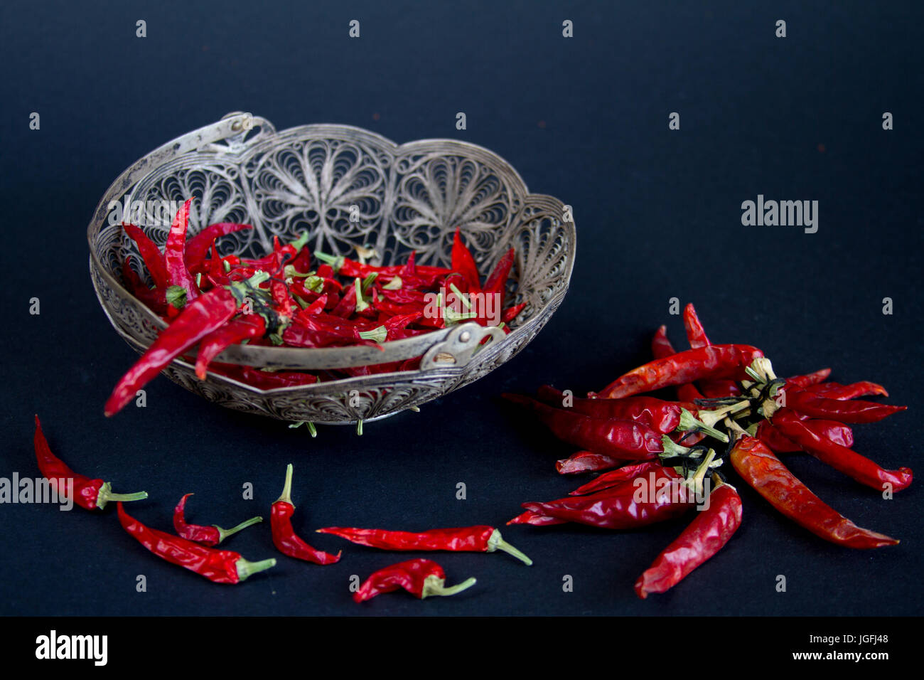 Red Chili pepper in a silver vase on a black background Stock Photo - Alamy