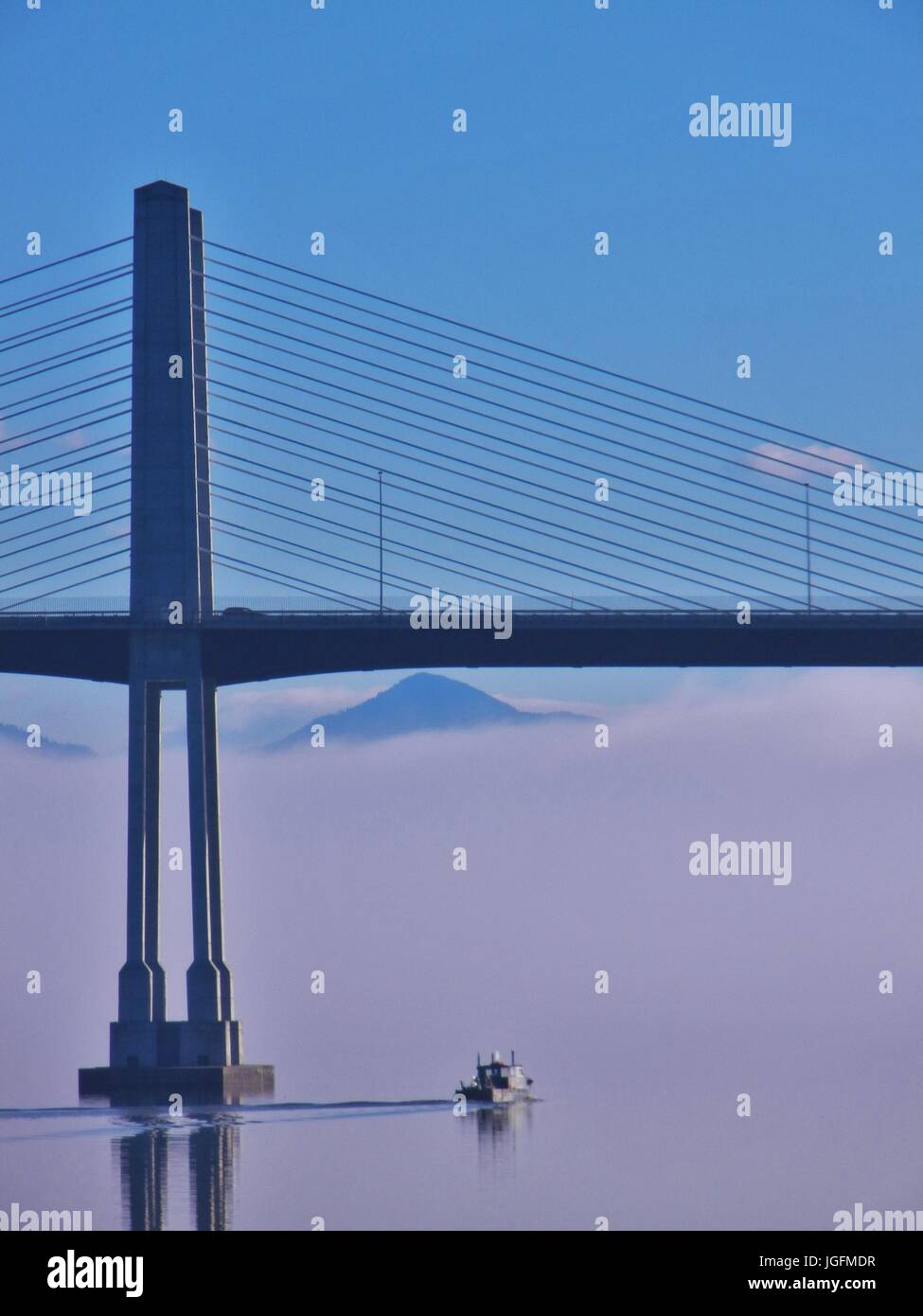 A small boat sails under a bridge into fog Stock Photo - Alamy