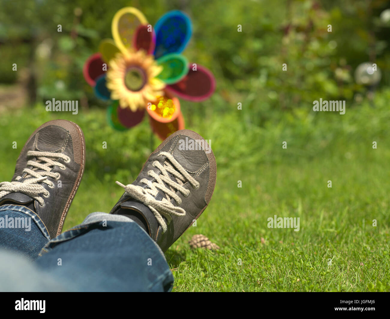Human feet wearing sport shoes in focus and a backyard garden in the ...