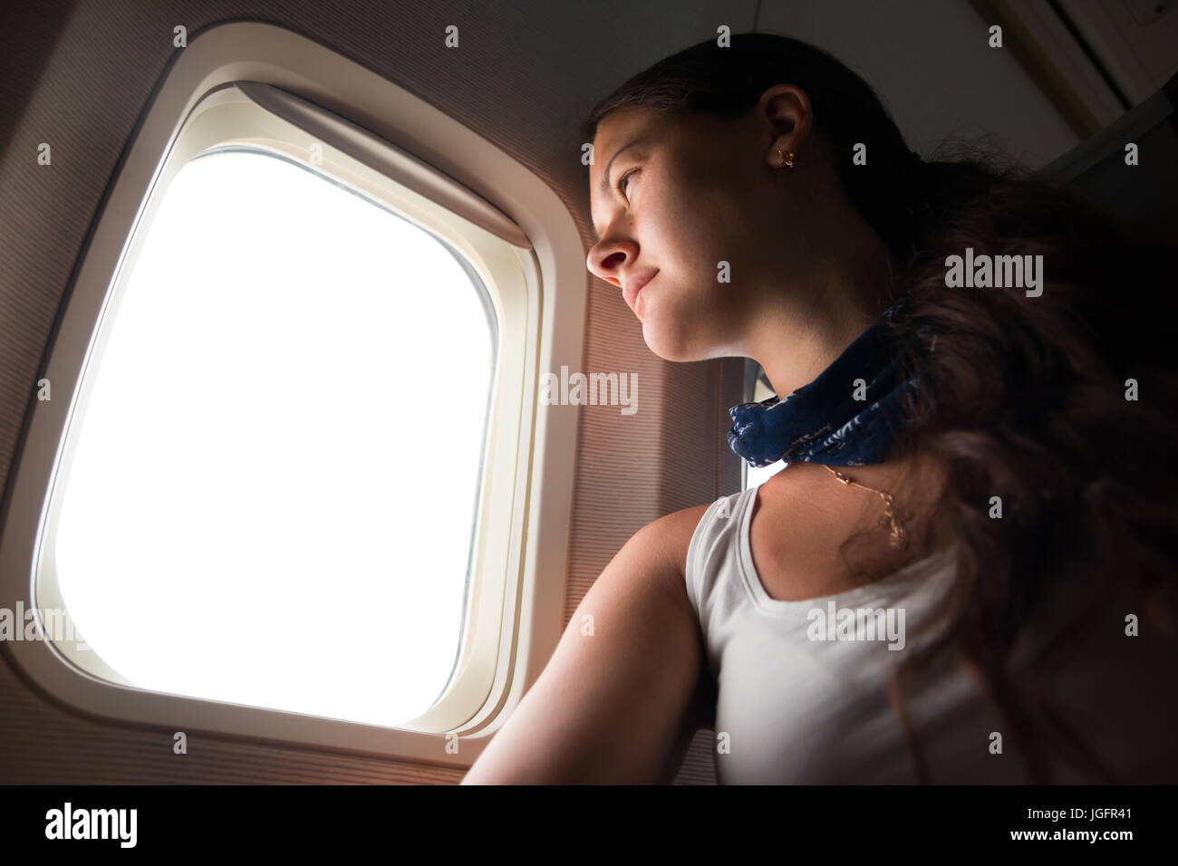 Young woman looking through window in airplane during fly Stock Photo ...