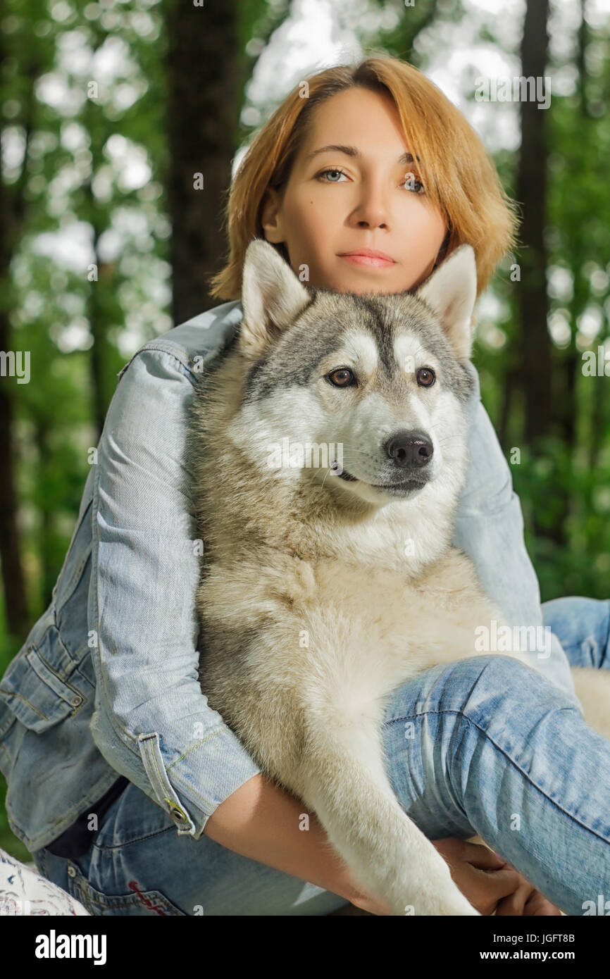 Beautiful girl with a husky breed dog in sunny weather walking outdoors ...