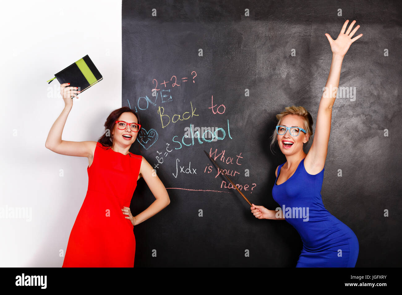 Two young attractive female students at school board. They are looking ...
