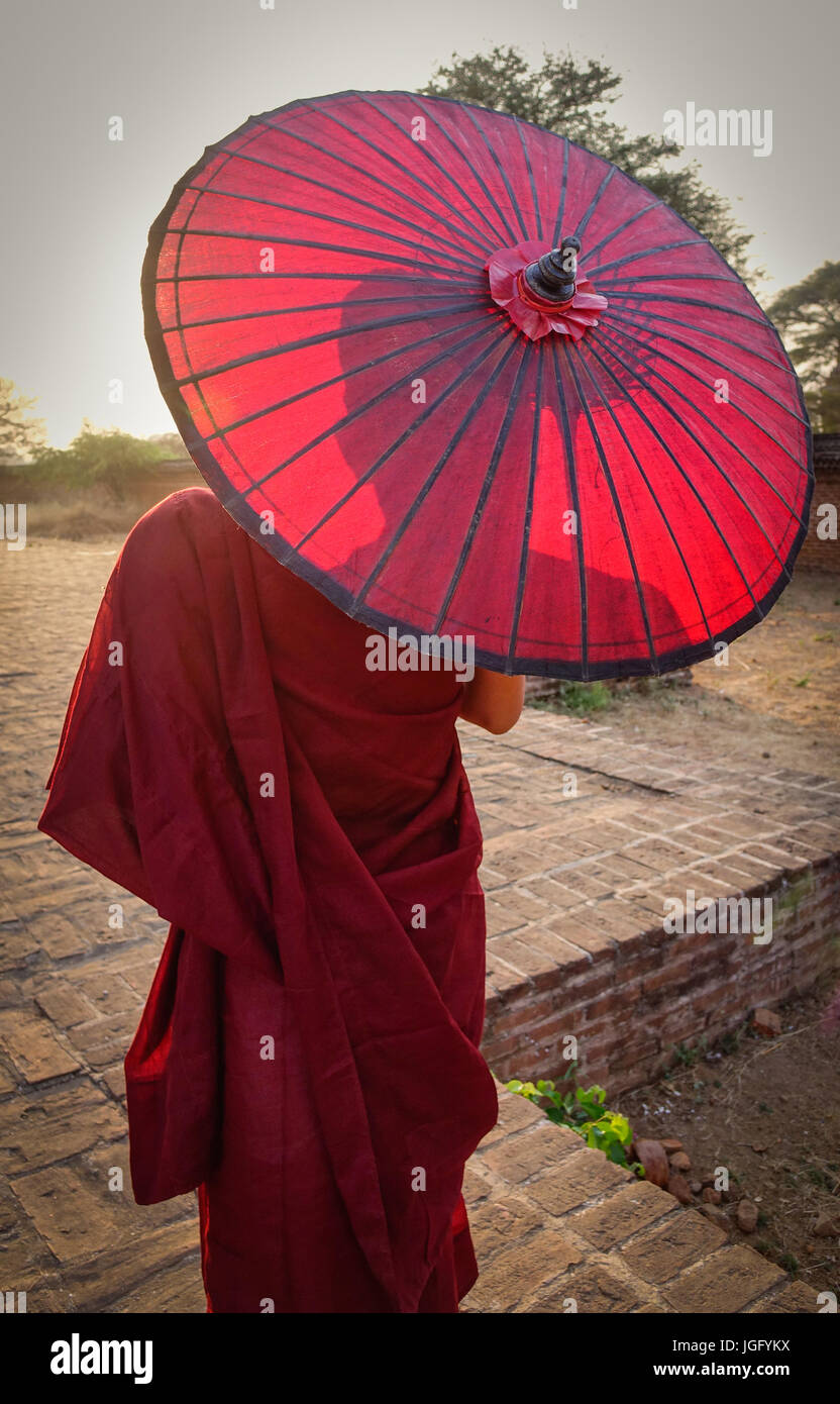 A Buddhist monk in the red robe with umbrella at the pagoda Stock Photo ...