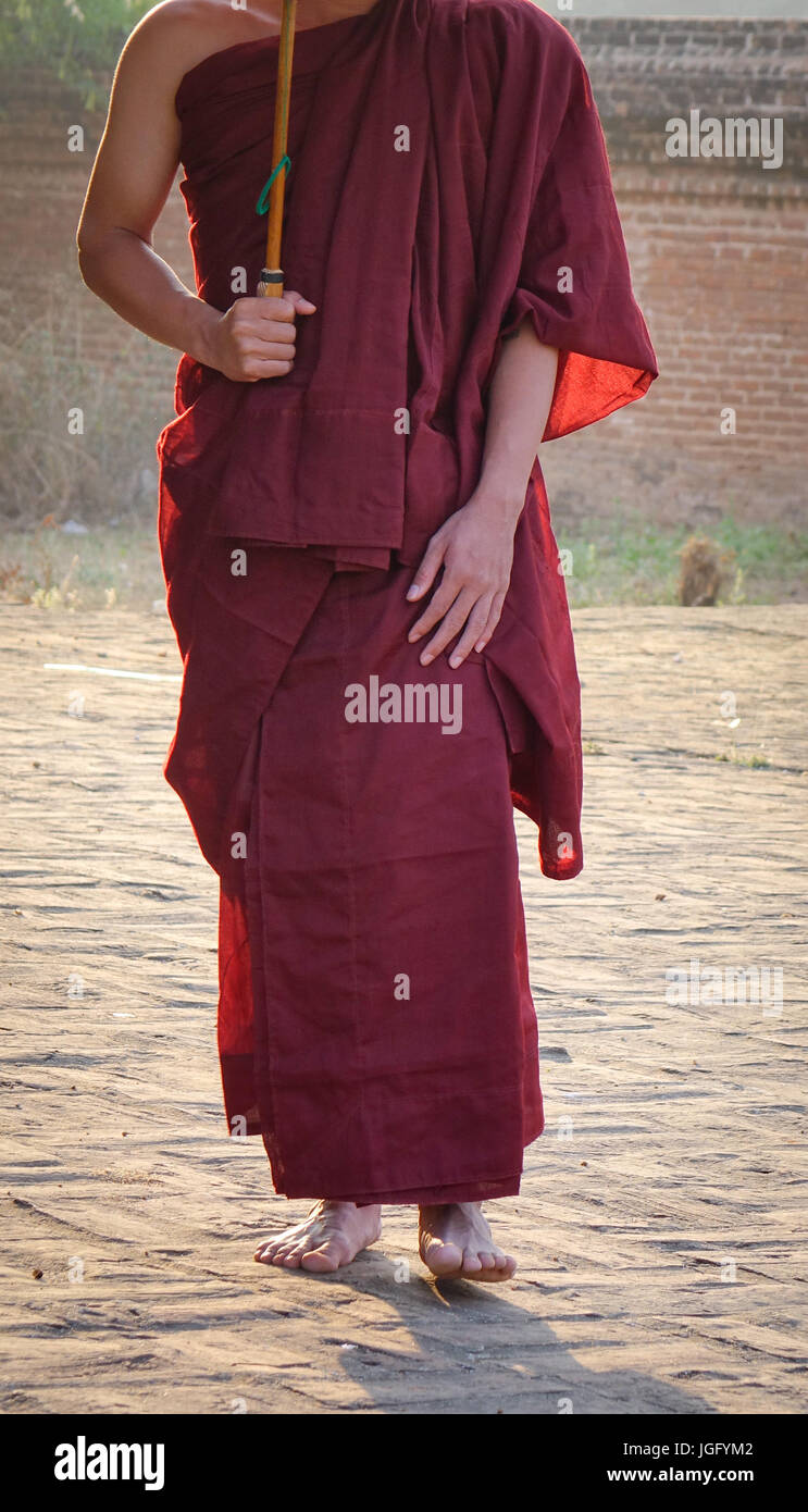 A Buddhist monk in the red robe with umbrella standing at the pagoda ...